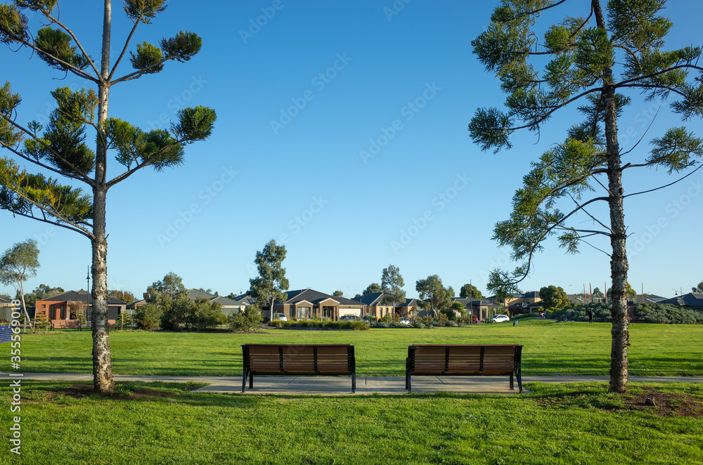 Two public park bench in a suburban park with some Australian homes in ...