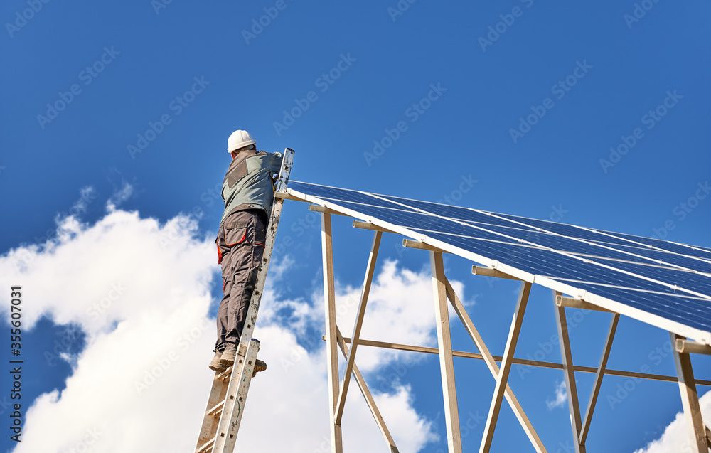 Side view of male worker installing solar panels and support structures ...