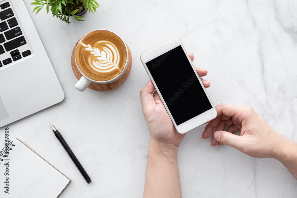 Hands holding white smartphone with blank screen over white marble ...
