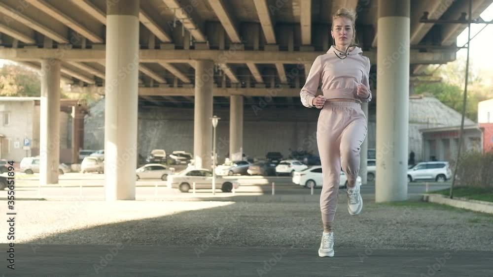Running in place. young Caucasian girl in headphones in sports clothes ...