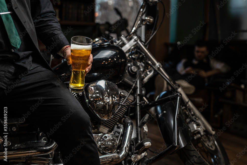 Biker sitting on a custom motorcycle with a glass of shiny craft beer ...