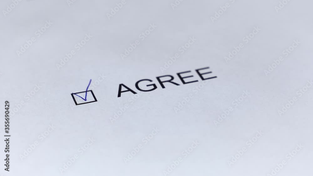 Man hand draw a tick in AGREE checkbox on white paper with pen ...
