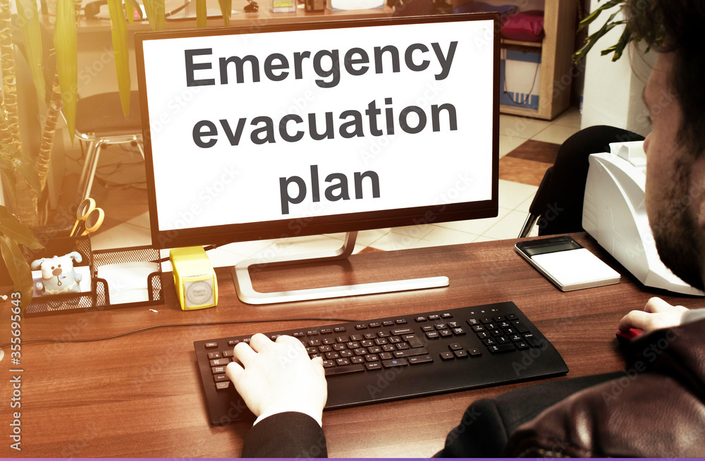 male and female hand, computer with text "Emergency evacuation plan ...
