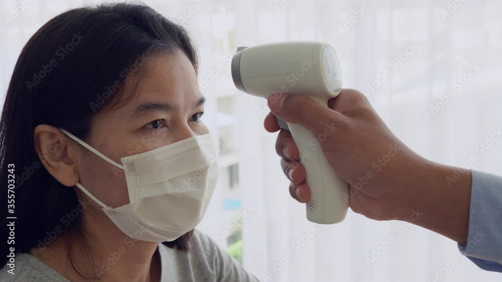doctor using infrared thermometer to measure temperature of sick asian ...