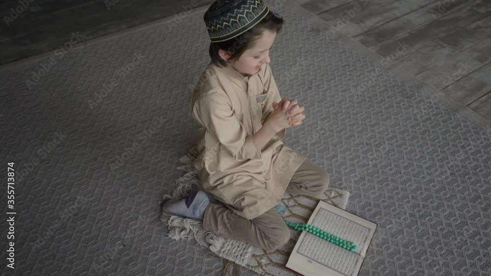 Video Stock Adorable muslim kid read the Quran in prayer hat and arabic ...
