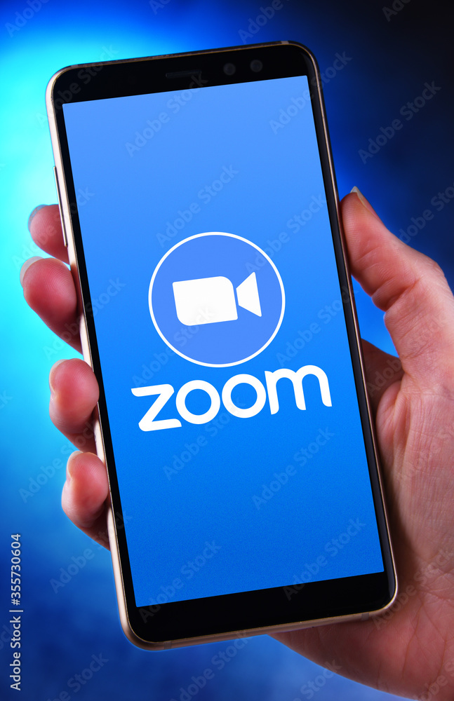 Hand holding smartphone displaying logo of Zoom Stock Photo | Adobe Stock