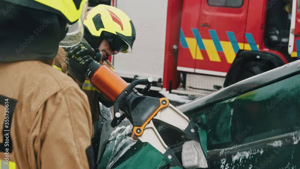 Fireman trying to cut open car door to save person involved in the ...
