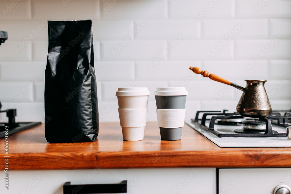 Coffee brewing at home in jezve on gas oven. Black coffee pack and cups ...