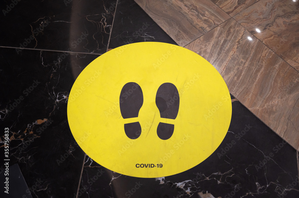 yellow warning sticker on the floor to keep your distance during ...
