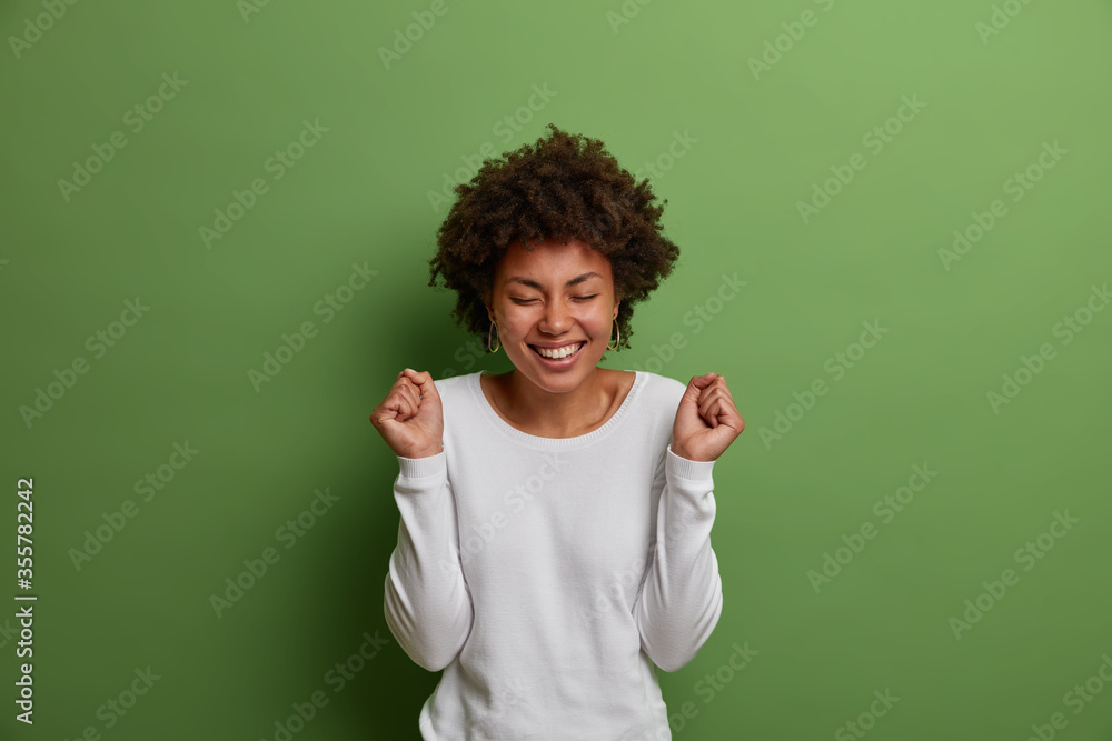 Finally I gained it! Cheerful successful woman raises hands with ...
