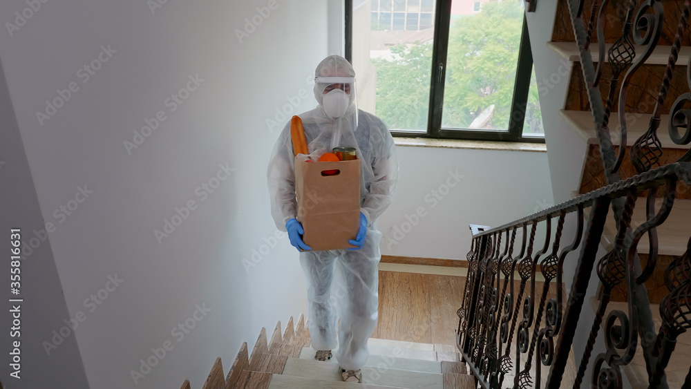 Volunteer delivering food order wearing coverall suit in covid-19 ...