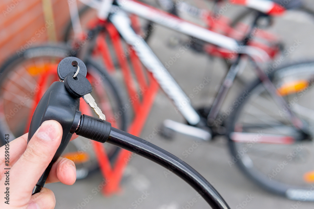 security and safety concept, key lock on bicycle wheel in parking ...
