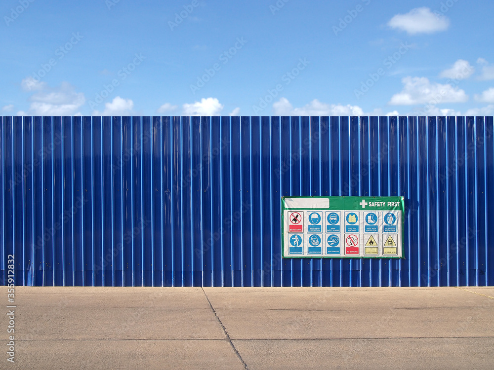 green vinyl warning sign with various safety symbols hanging on dark ...