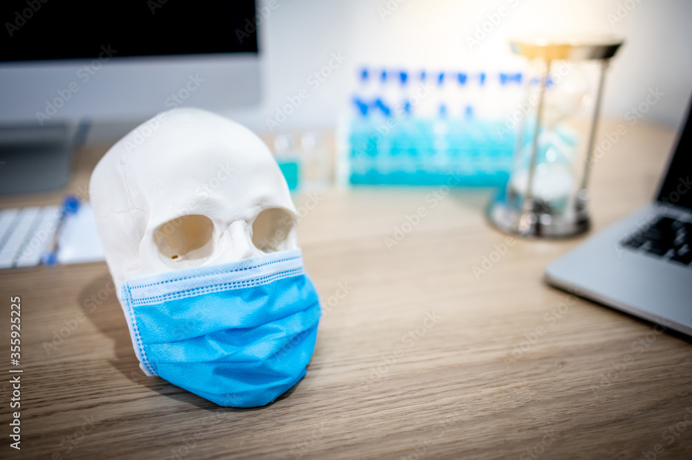 Human skull or cranium head wearing blue surgical mask with test tube ...