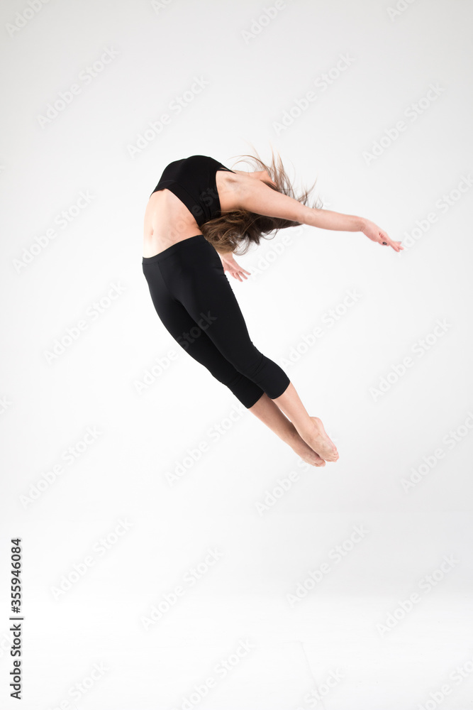 Jumping girl with body bending back on white background. The gymnast ...