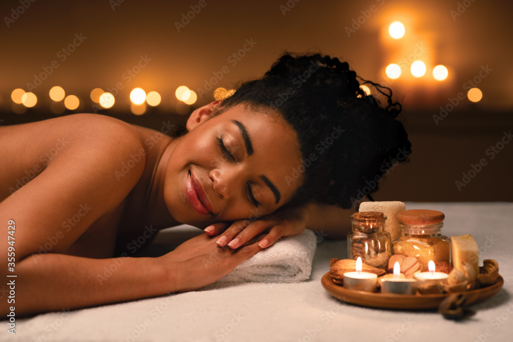 Foto de Smiling african woman lying on massage table at spa do Stock ...