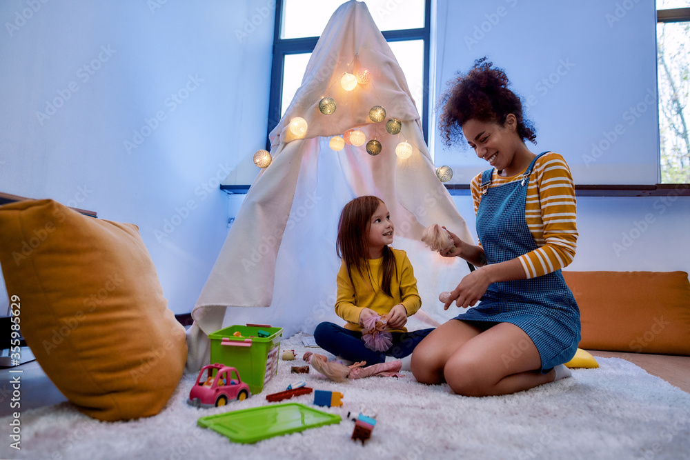 Caring for the future. African american woman baby sitter entertaining ...