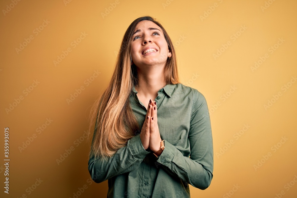 Young beautiful blonde woman with blue eyes wearing green shirt over ...