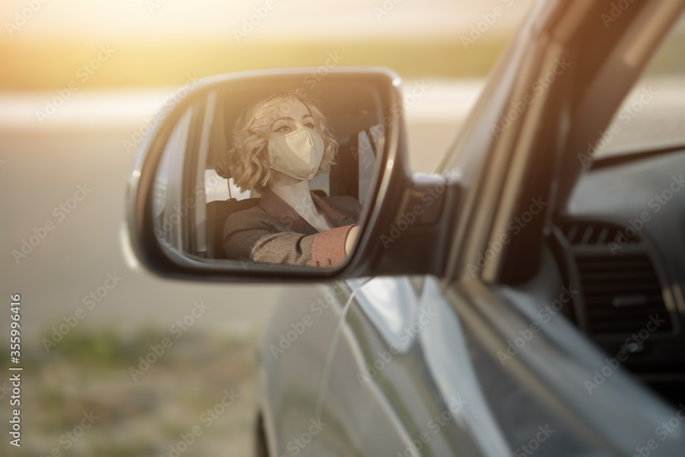Beautiful girl driver with a mask on her face, sitting at the wheel of ...