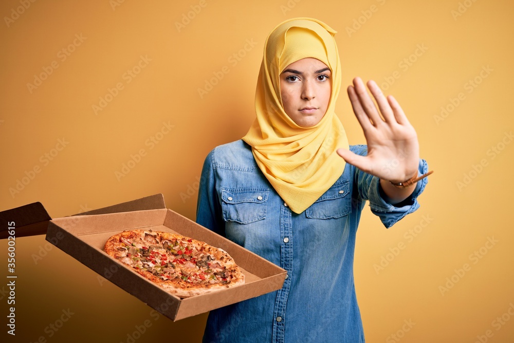 Young girl wearing muslim hijab holding box with Italian pizza over ...