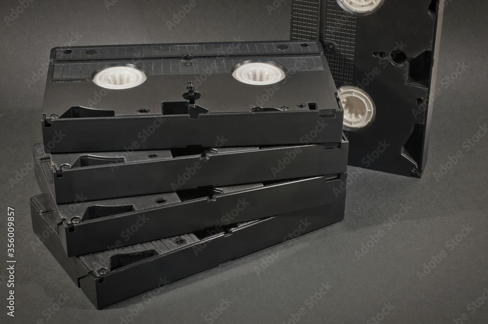 a stack of black vhs video cassettes on a black background. old film ...