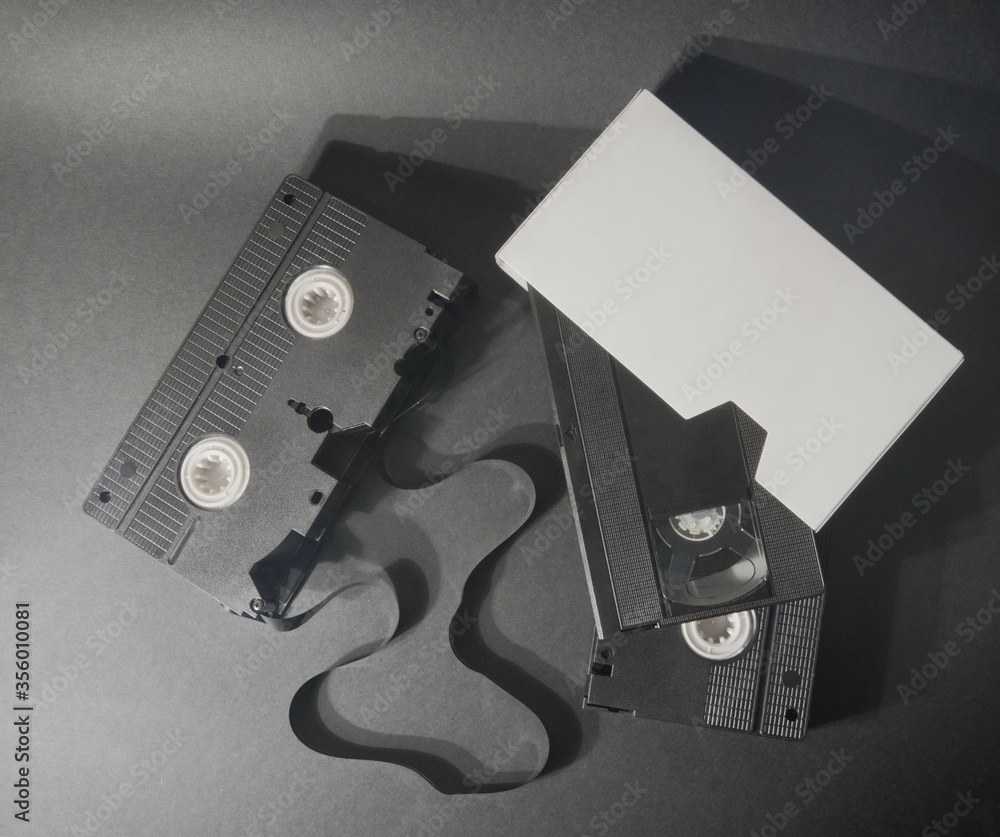 a stack of black vhs video cassettes on a black background. old film ...