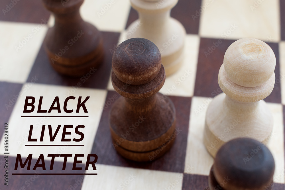 Black and white chess pieces on a chessboard.Inscription BLACK LIVES ...