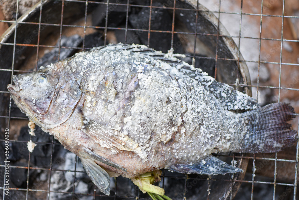 Fish on grill - Close up of tilapia fish grilled with salt on fire and ...