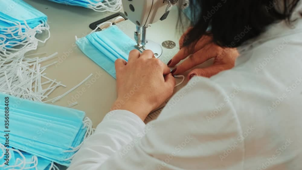 Woman hands using the sewing machine to sew the face medical mask ...