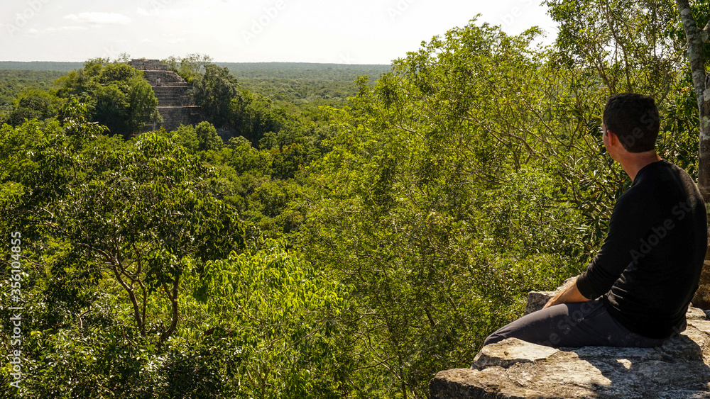 Male person looking at the ancient Maya ruins of Calakmul in the thick ...