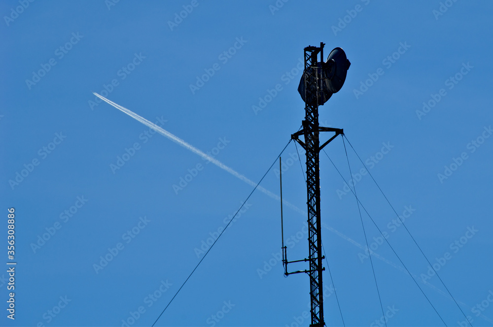Small rural microwave relay tower with single pole antenna and contrail ...