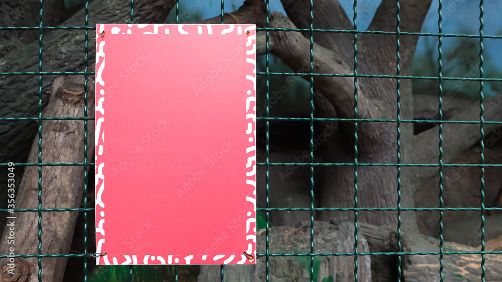 Red blank metallic signboard on a fence for artwork template design ...