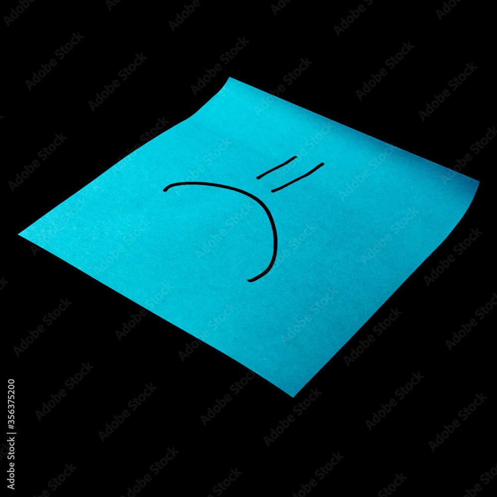 Paper sticker with the image of the symbol of a sad emoticon on dark ...
