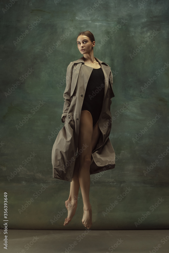 In flight. Graceful classic ballerina dancing, posing isolated on dark ...