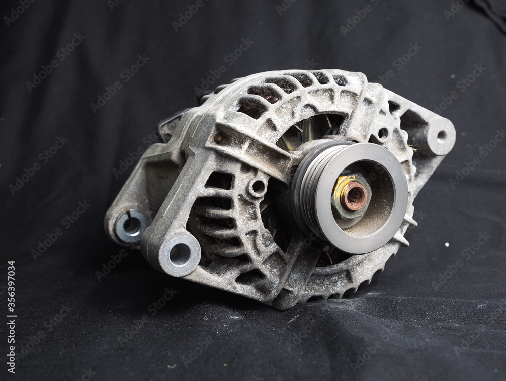 Used, dirty unclean alternator car part shot on a black background to ...