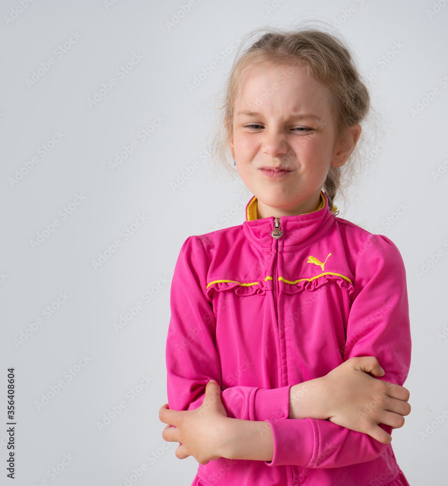 Little girl standing with arms crossed on her chest, showing a grimace ...