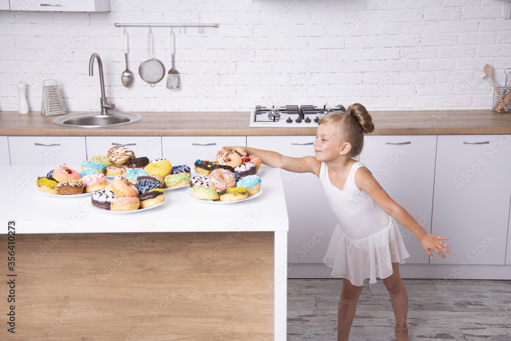 Little girl reaches for donuts. Little girl wants donuts. Little girl ...