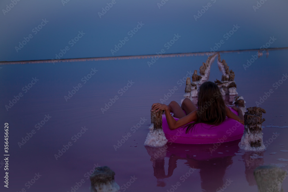 Rear view of girl swimming on ring in the sea or ocean at the ...