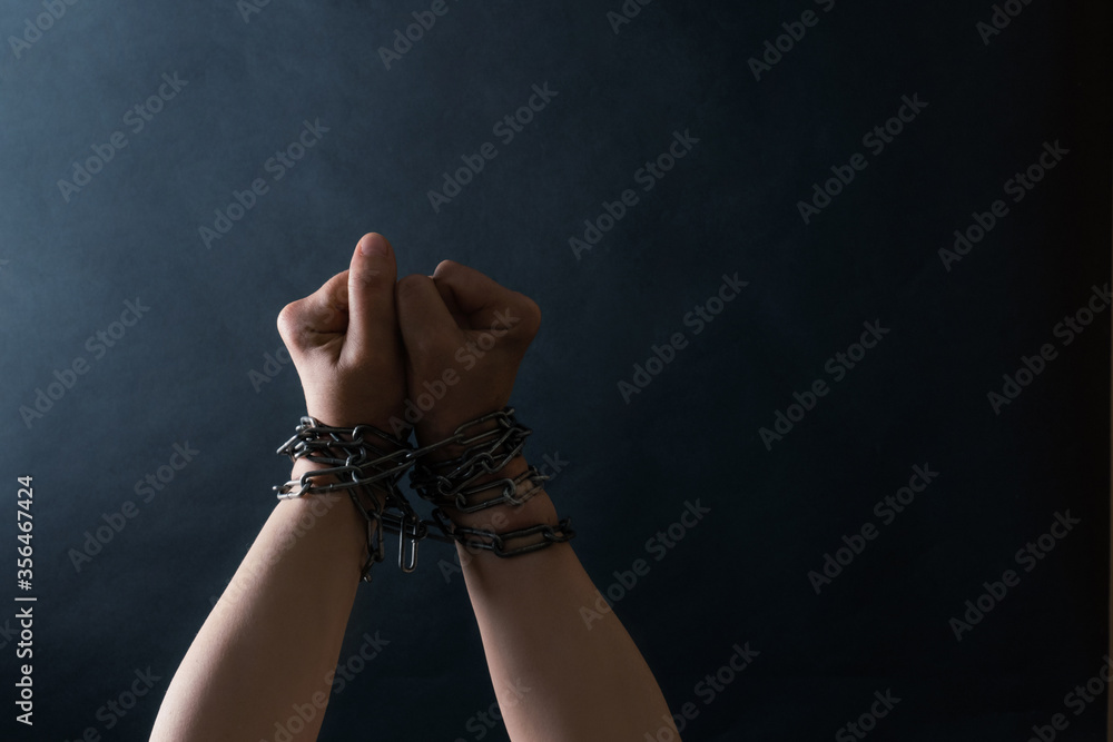 Fists of Hands are chained in chains on the black background, concept ...