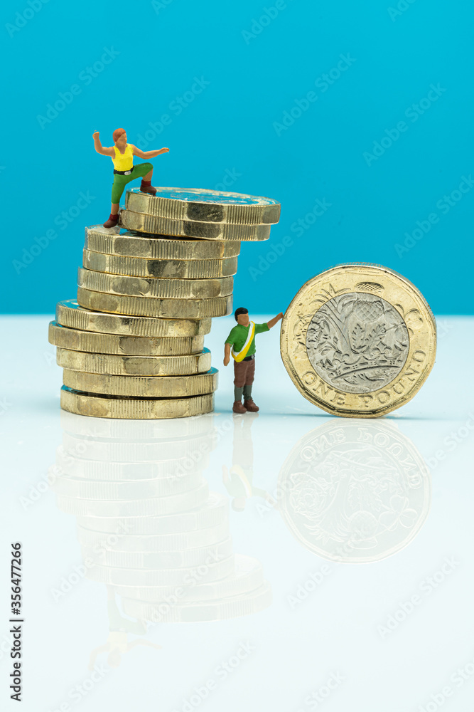 pile of one pound coins with miniature figures climbing plus one pound ...