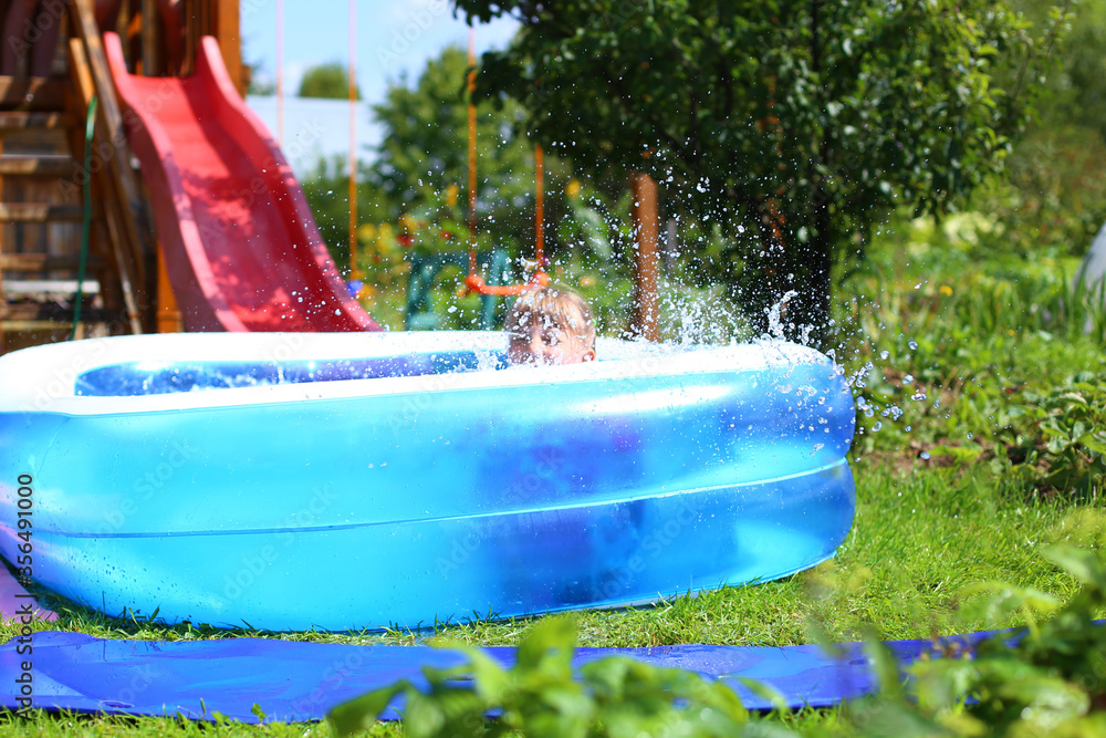 Staycation at home. Little girl in swimsuit rolls down slide into ...