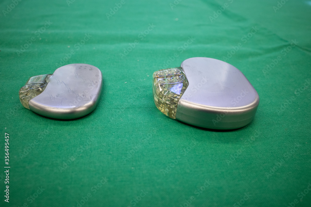 pacemaker lies directly next to a defibrillator on a green surgical ...
