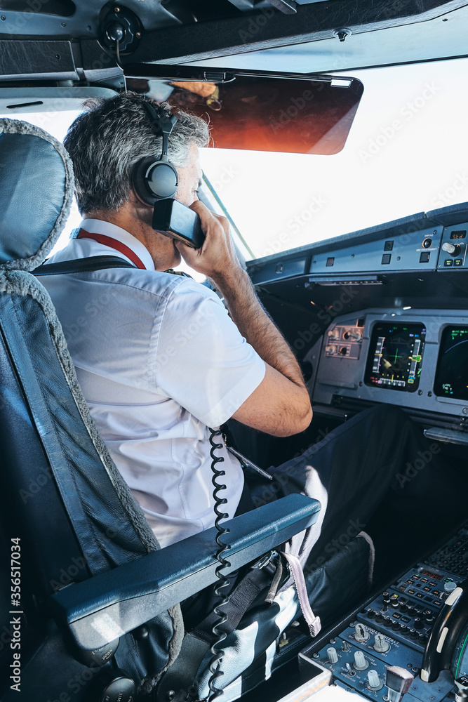 Side view of male captain communicating via VHF radio while sitting in ...