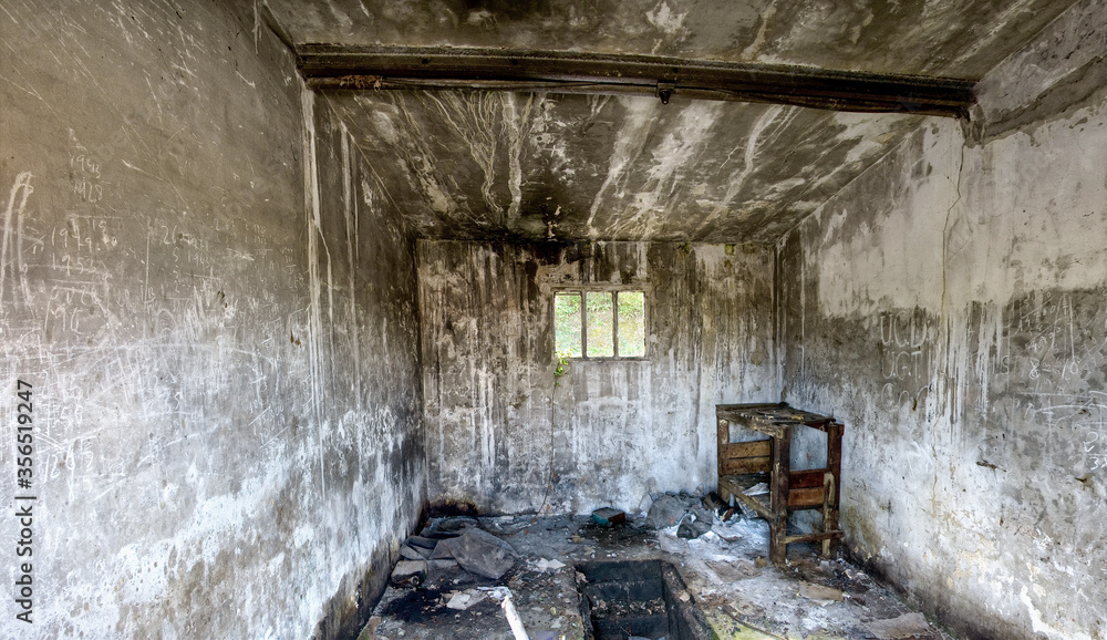 Empty small room with weathered concrete walls and dirty floor with ...