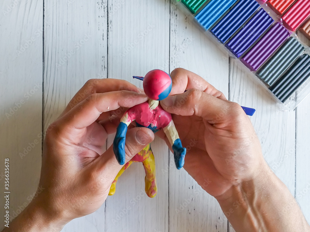 The hands of a male craftsman work on a human sculpture, sculpting from ...
