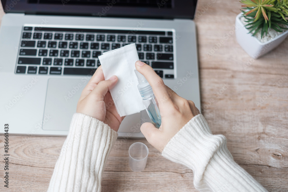 Woman cleaning laptop by wet wipes tissue and alcohol disinfectant on ...