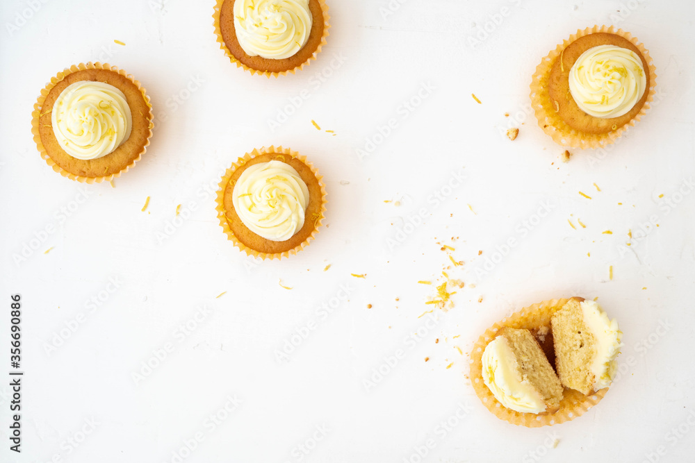 A top down view of five lemon cupcakes with vanilla frosting. One ...