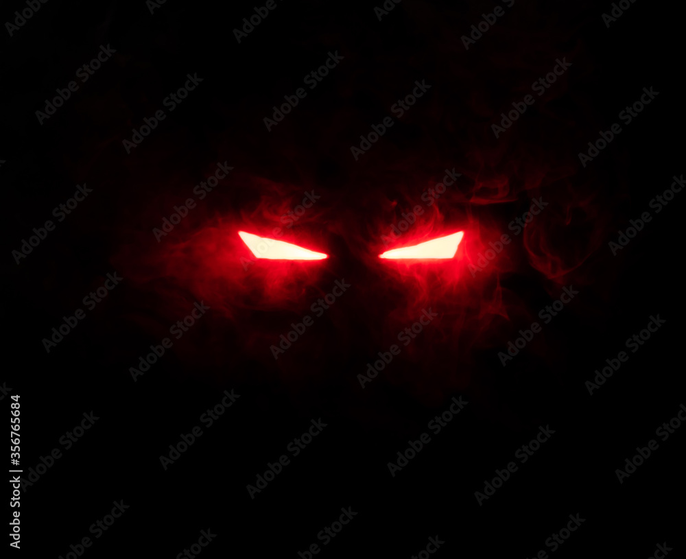 Ominous luminous eyes staring out of the darkness illuminate with rays ...
