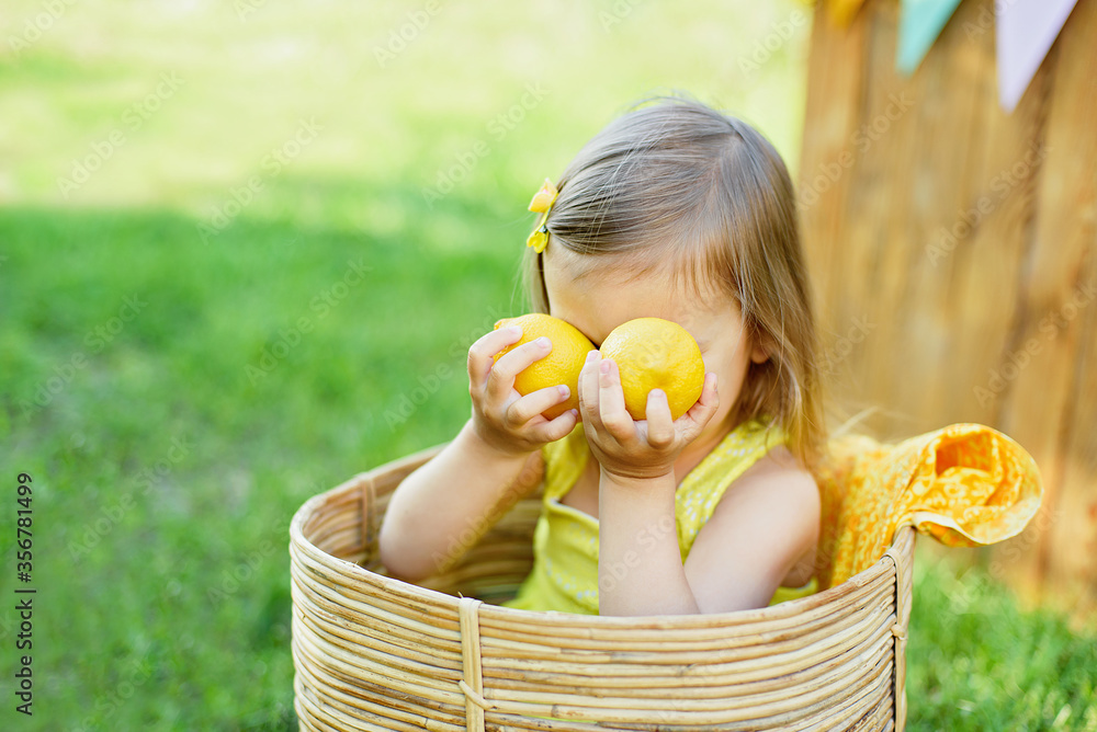 Little child girl with lemons covering eyes at lemonade stand in park ...