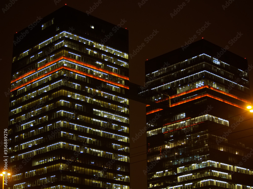Two high-rise buildings connected by a transition in the night city ...